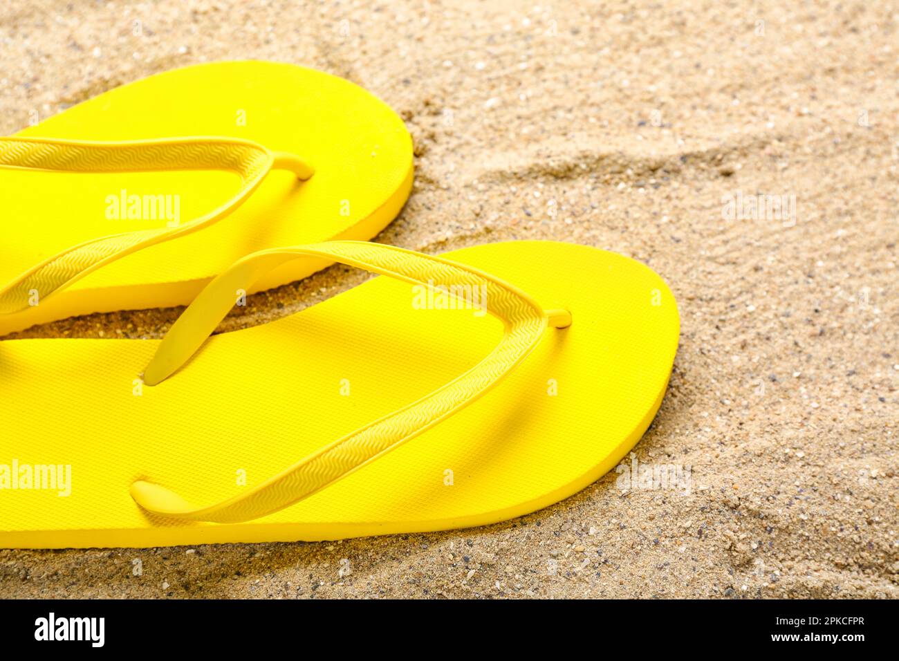 Yellow flip-flops on sand, closeup Stock Photo - Alamy