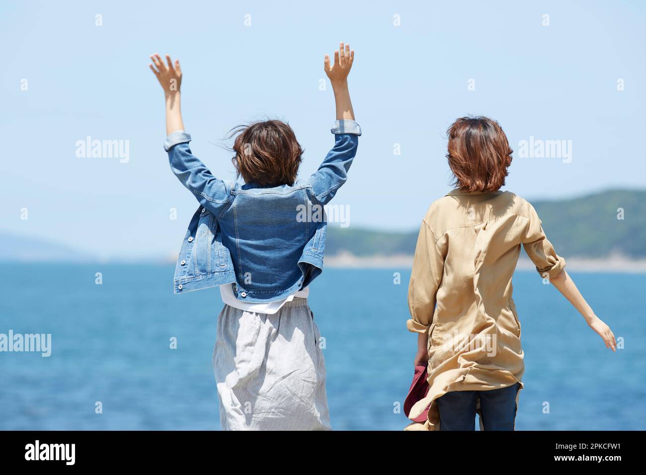 Back view of two women waving to the sea Stock Photo - Alamy