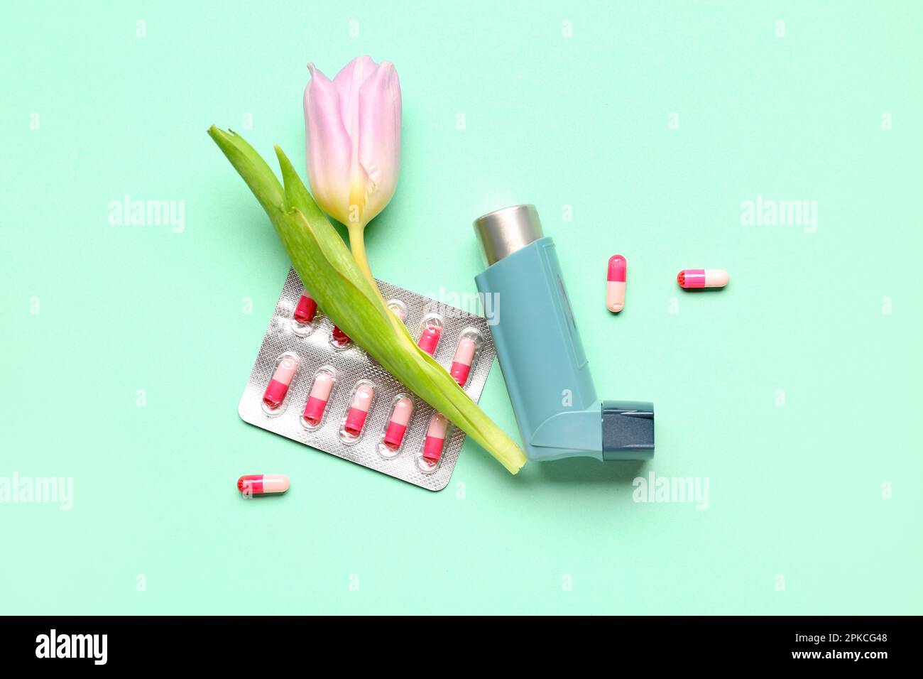 Asthma inhaler with pills and tulip on green background Stock Photo - Alamy