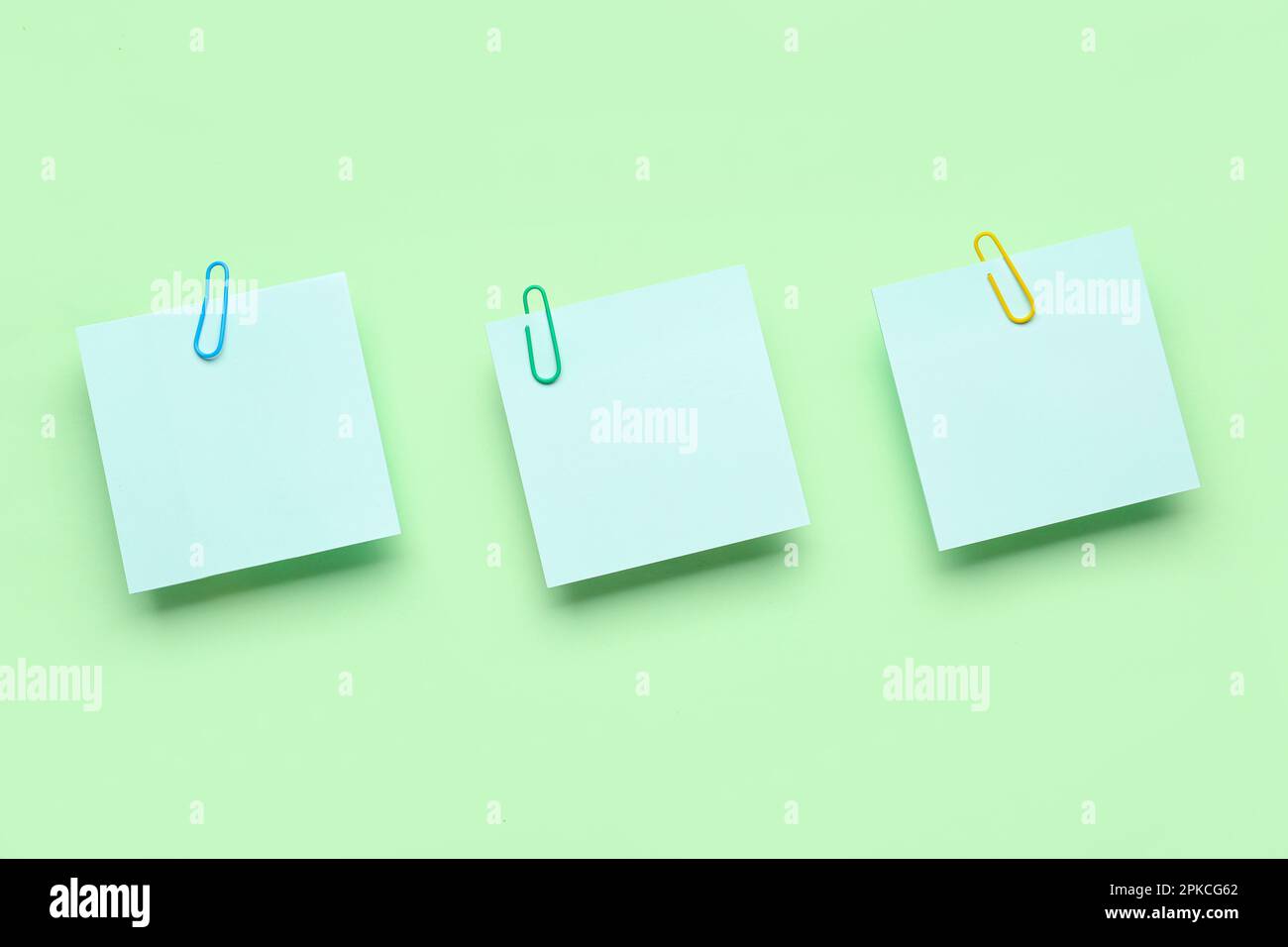 Sticky notes with paper clips on green background Stock Photo - Alamy
