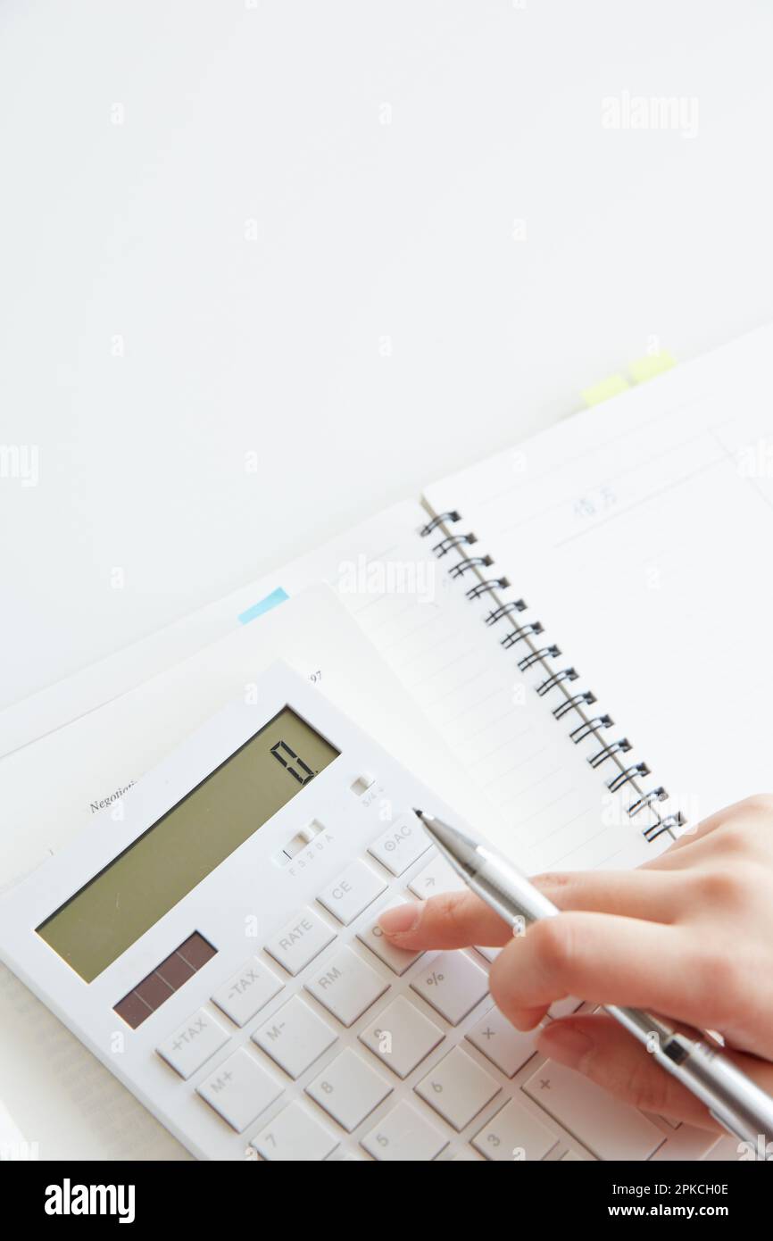 Woman's hand using a calculator to calculate on an open notebook Stock ...