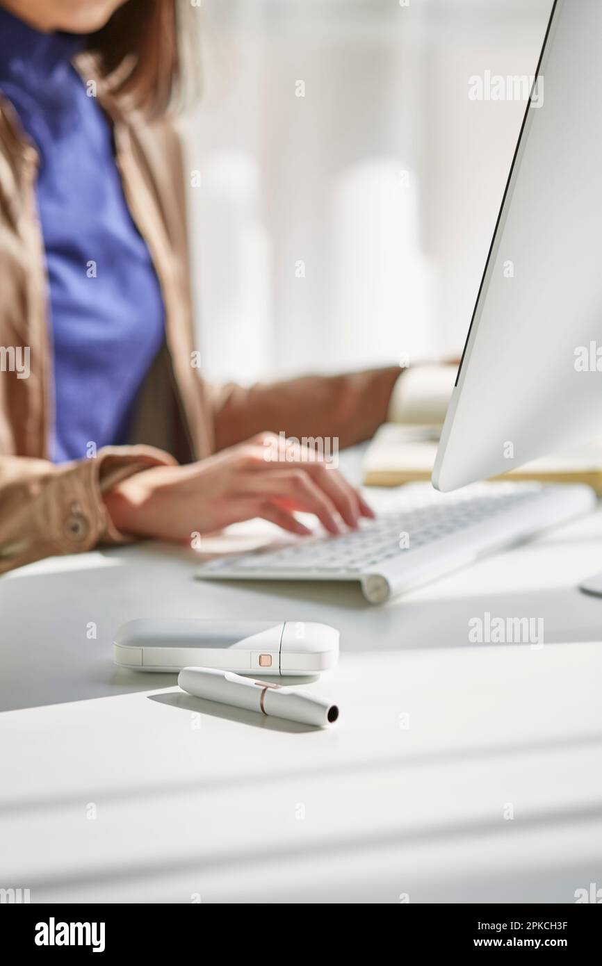 A woman at her desk smoking an IcoS Stock Photo - Alamy