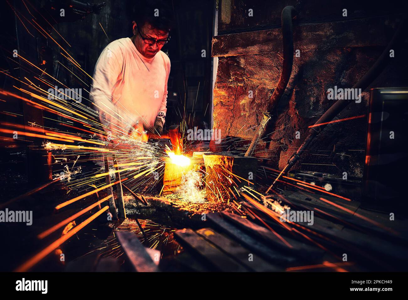 A man working in a cutlery factory with sparks flying Stock Photo - Alamy