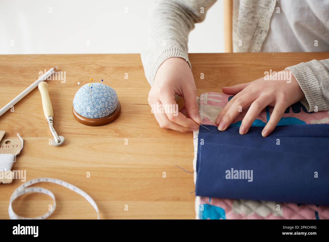 Woman's hand pointing a needle to a cloth on the table Stock Photo - Alamy