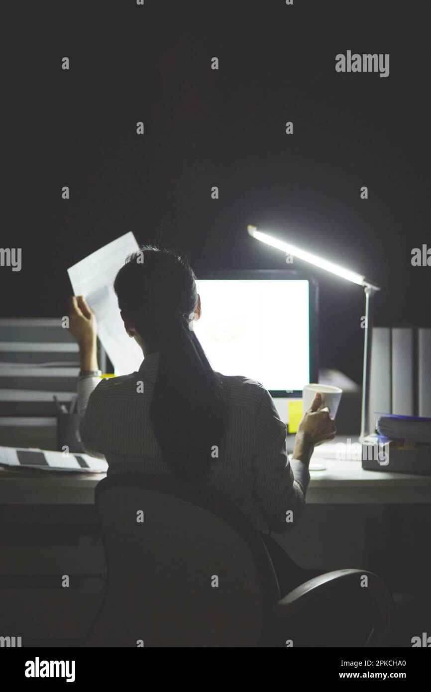 Back view of a woman working overtime Stock Photo - Alamy