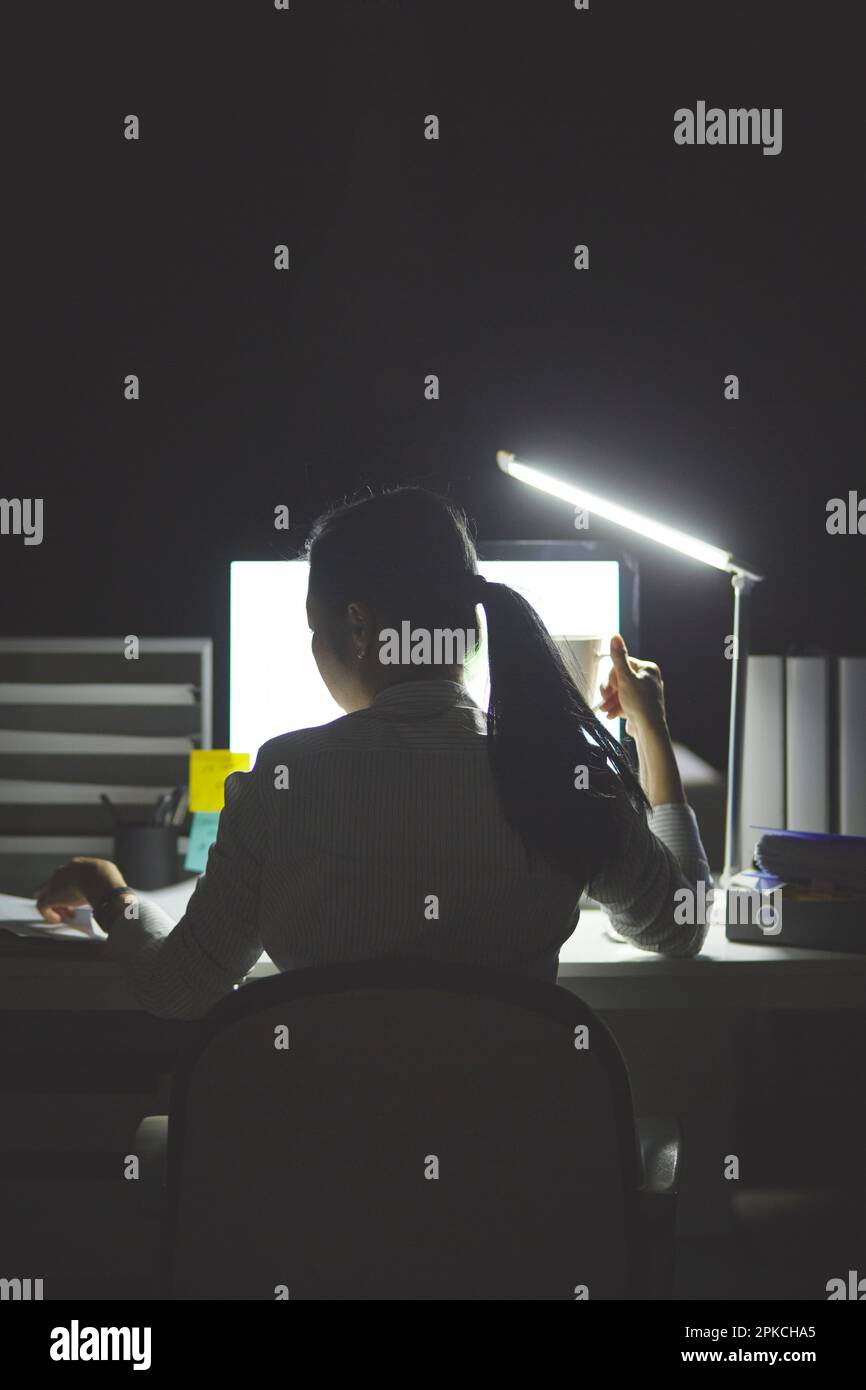 Back view of woman working overtime Stock Photo - Alamy