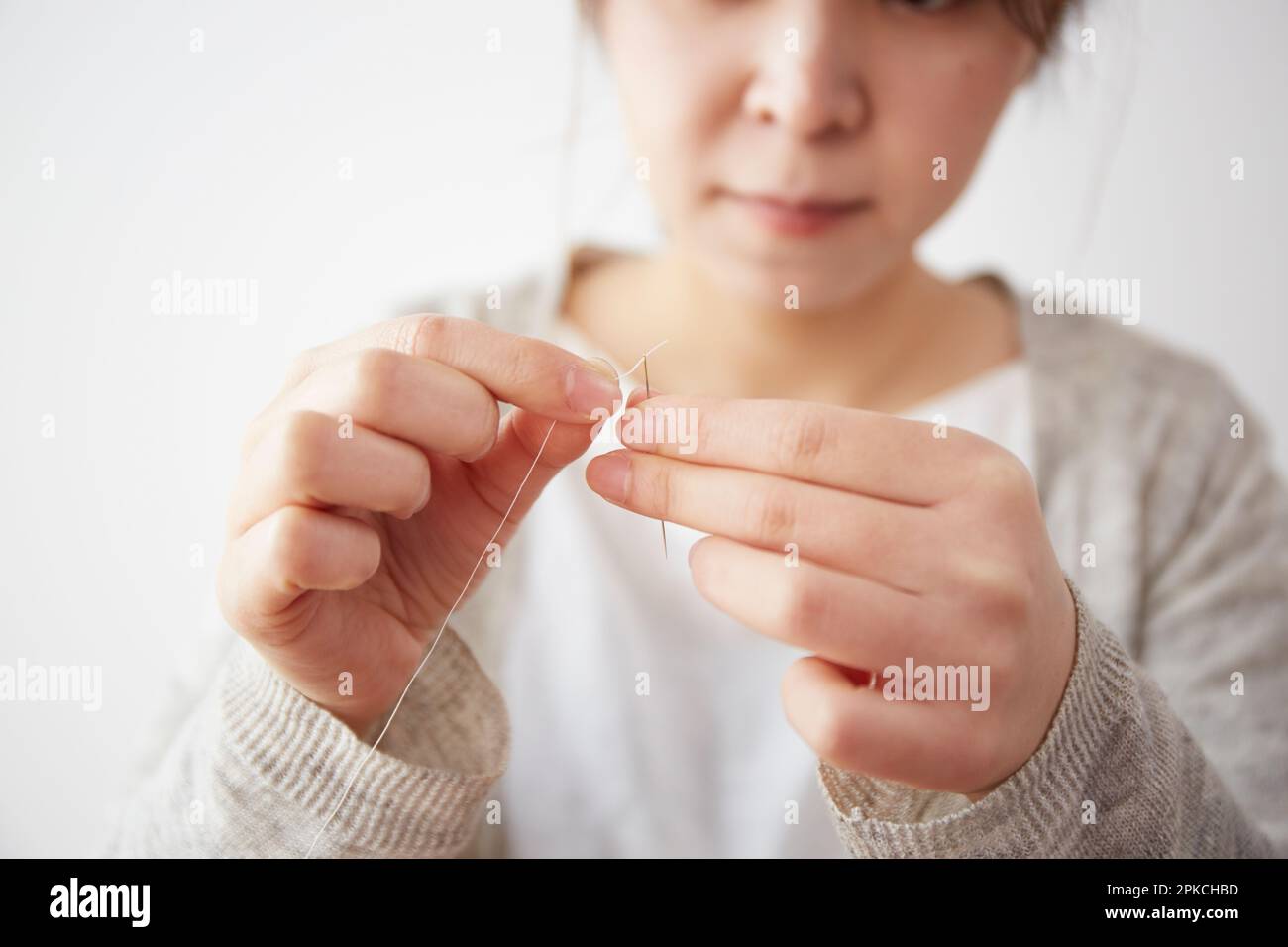 Woman threading a needle Stock Photo - Alamy