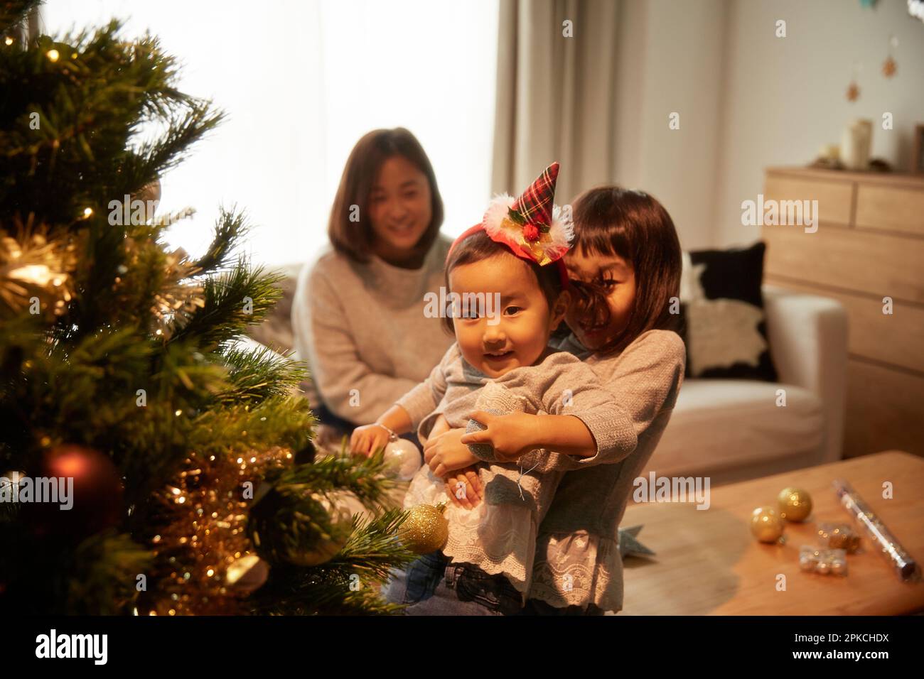 Sisters decorating a Christmas tree Stock Photo - Alamy