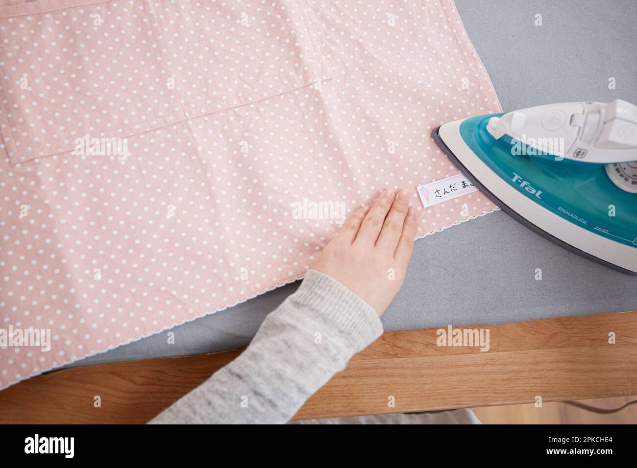 Woman attaching a name tag to an apron with an iron Stock Photo - Alamy