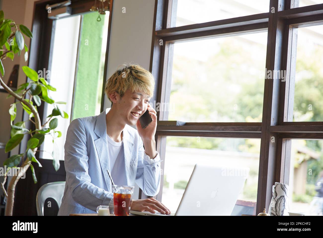 A man operating a computer while on the phone at a café Stock Photo - Alamy