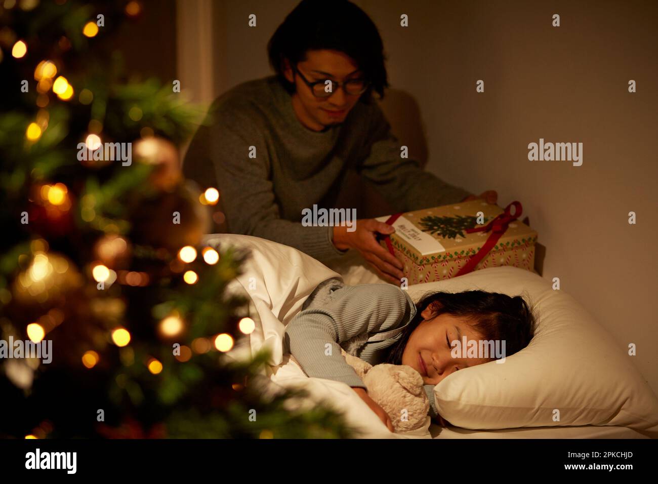 Father placing a Christmas present under the pillow of a sleeping girl ...
