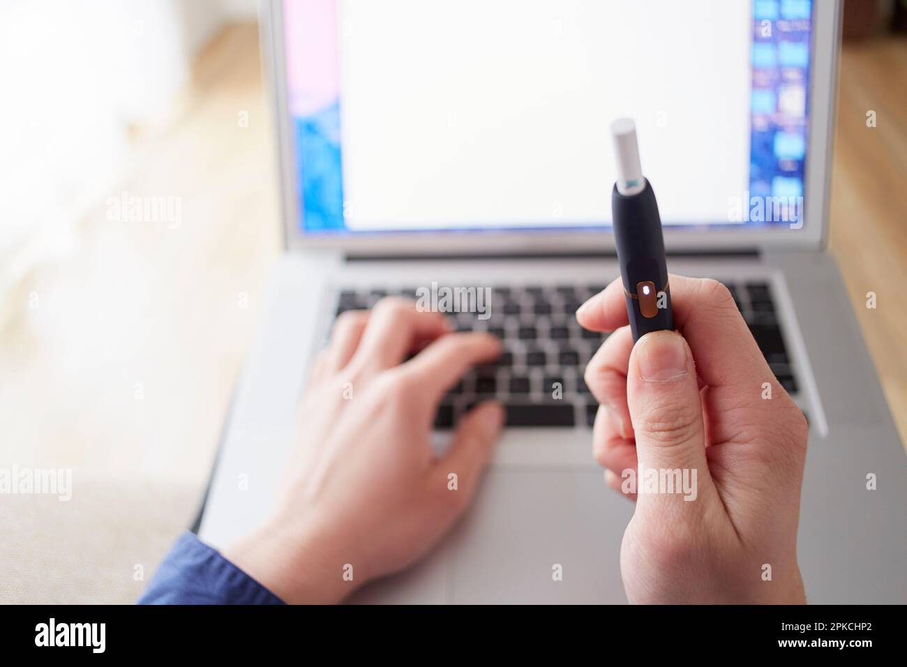 Man smoking an e-cigarette while on computer Stock Photo - Alamy