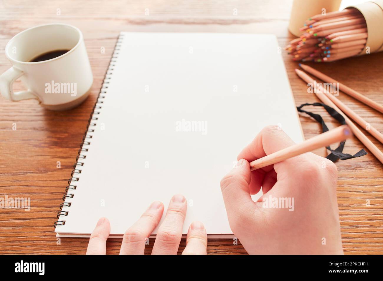Hand of a man trying to draw a picture in a sketchbook on a table Stock ...