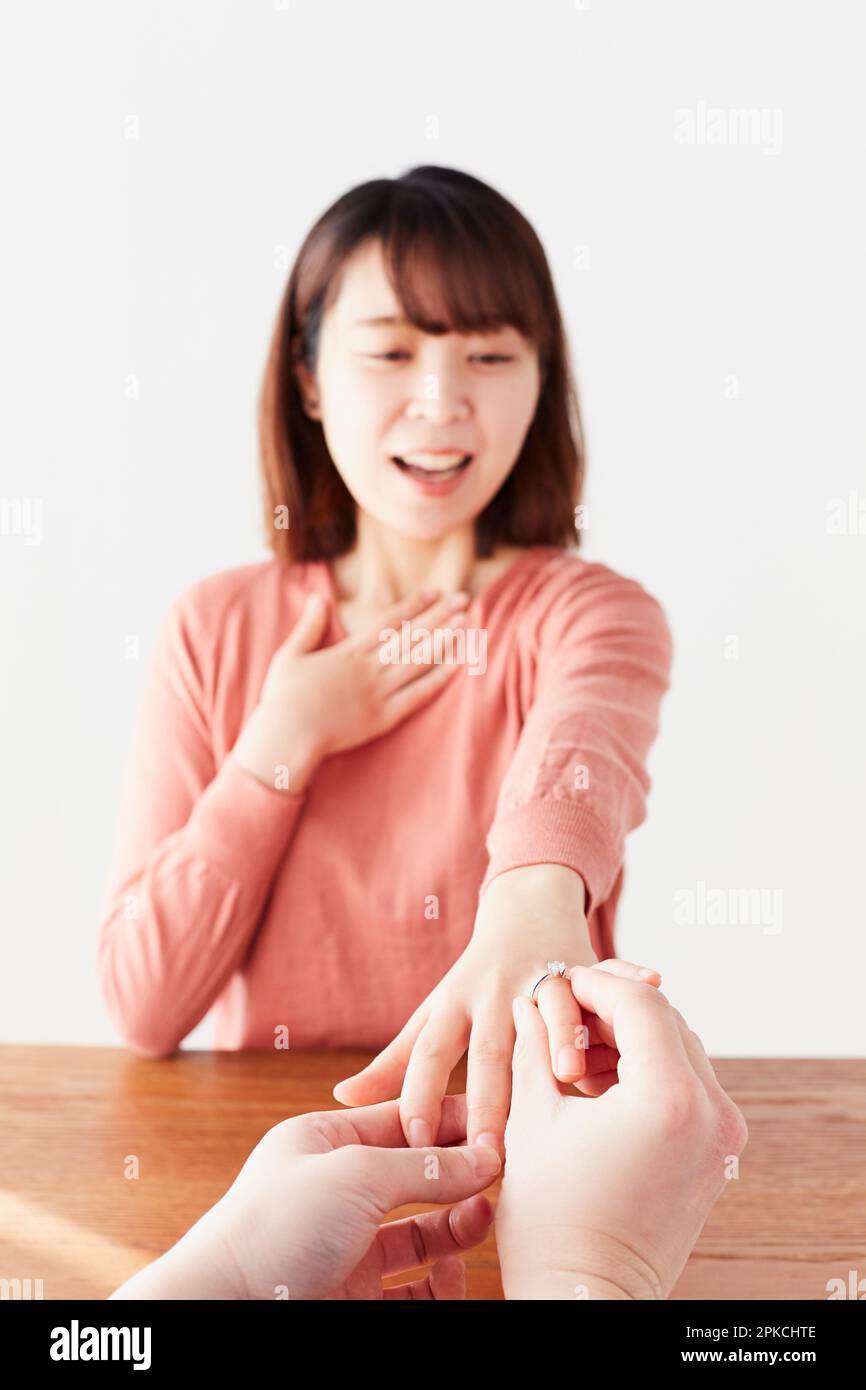 A woman pleased to receive an engagement ring and a man's hand putting ...