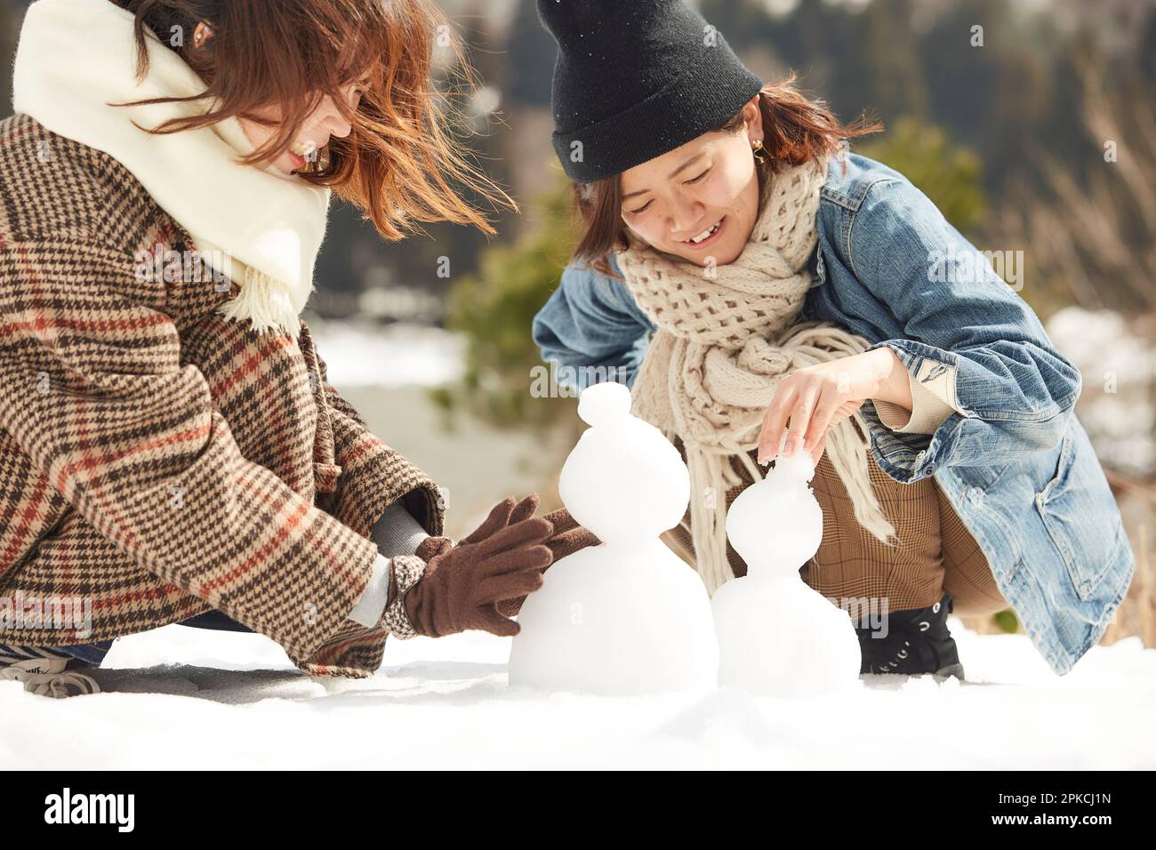 Two women making a snowman Stock Photo - Alamy