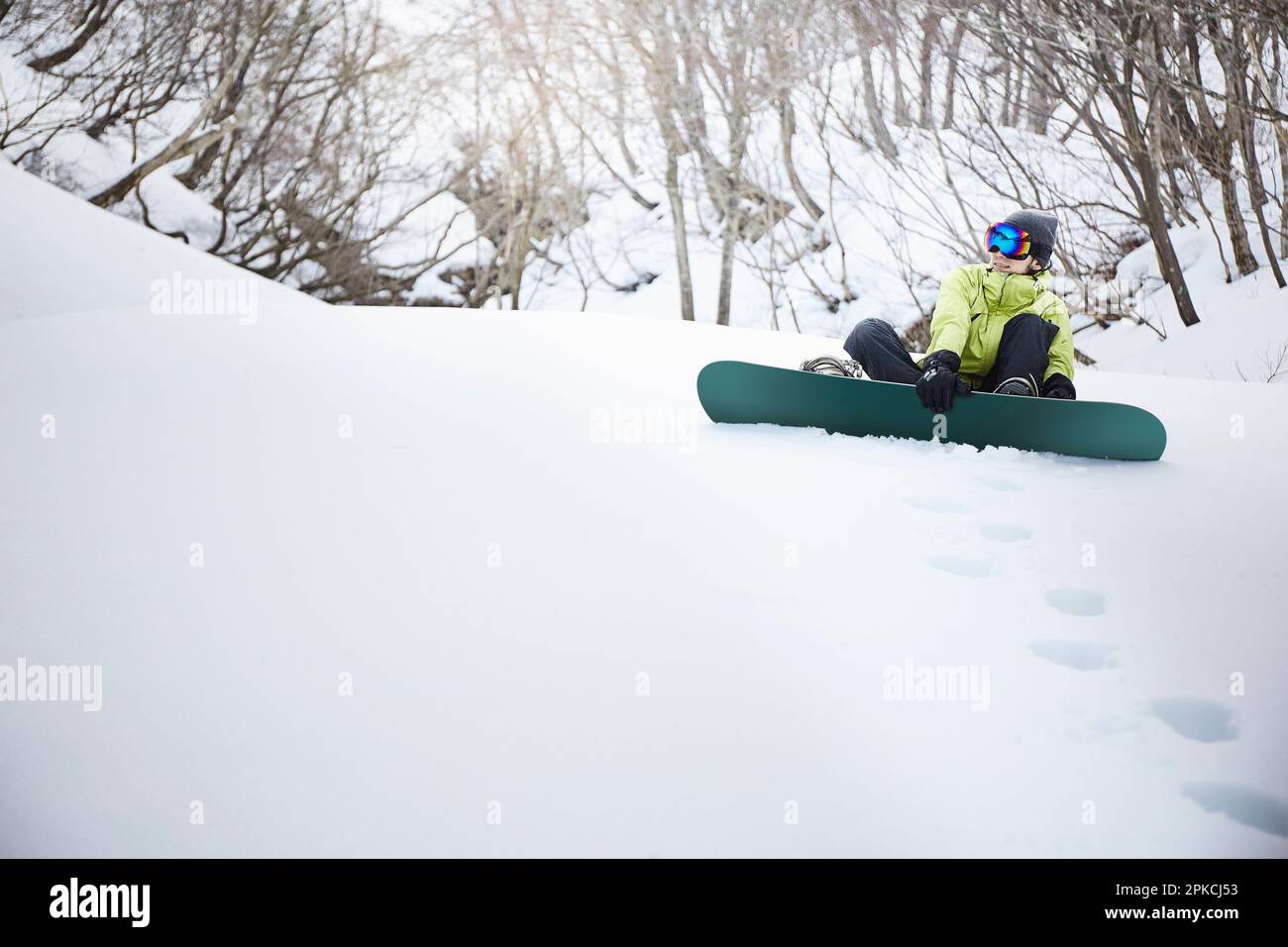 Snowboarder sitting on snow mountain Stock Photo - Alamy