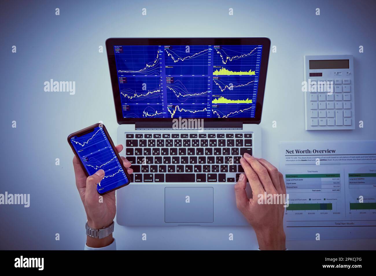 Man's hand with computer and smartphone showing stock chart Stock Photo ...