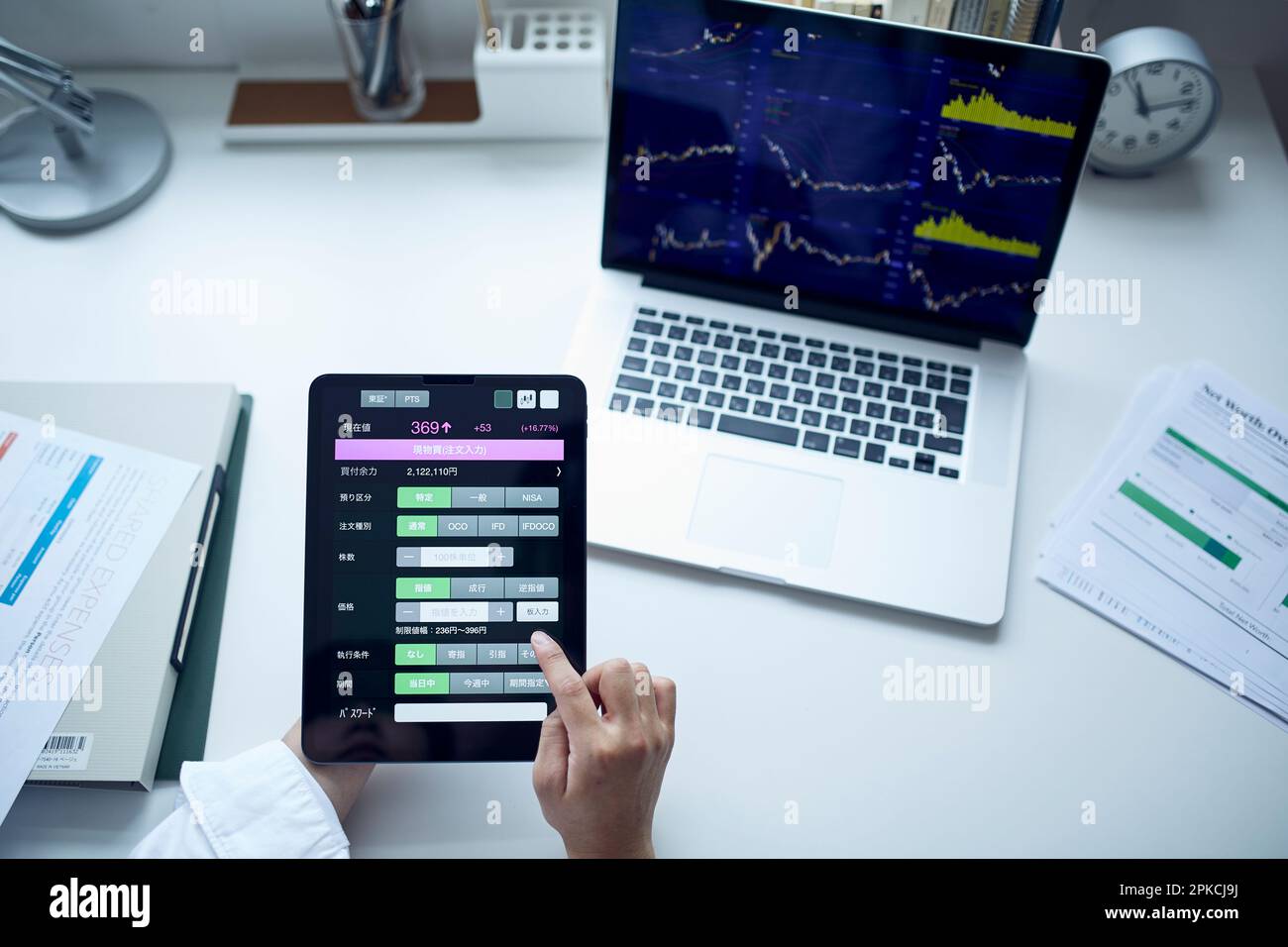Man placing a stock order with a tablet while checking his computer at ...