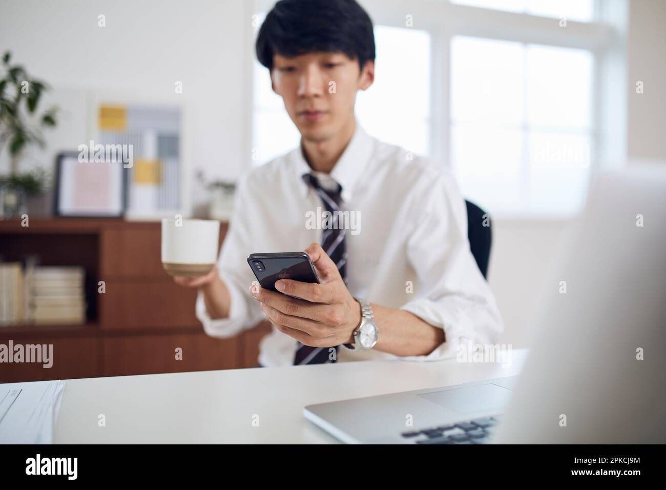 Office worker operating smartphone at his desk at home Stock Photo - Alamy