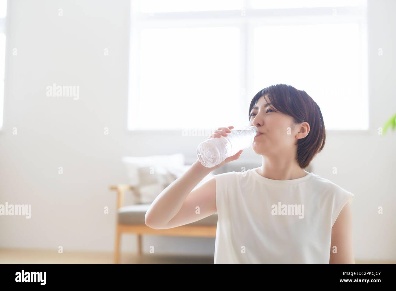 Woman rehydrating with a plastic bottle indoors Stock Photo - Alamy