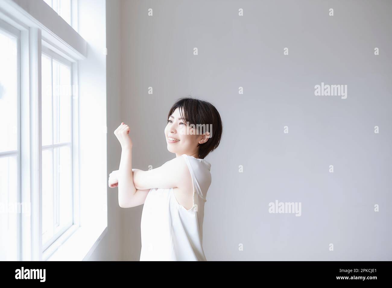 Woman stretching her arms while looking out the window Stock Photo - Alamy
