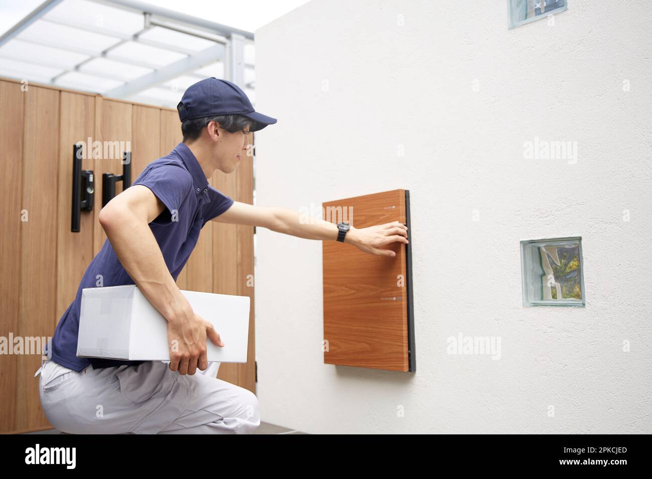 A parcel delivery man putting a package into a delivery box Stock Photo ...