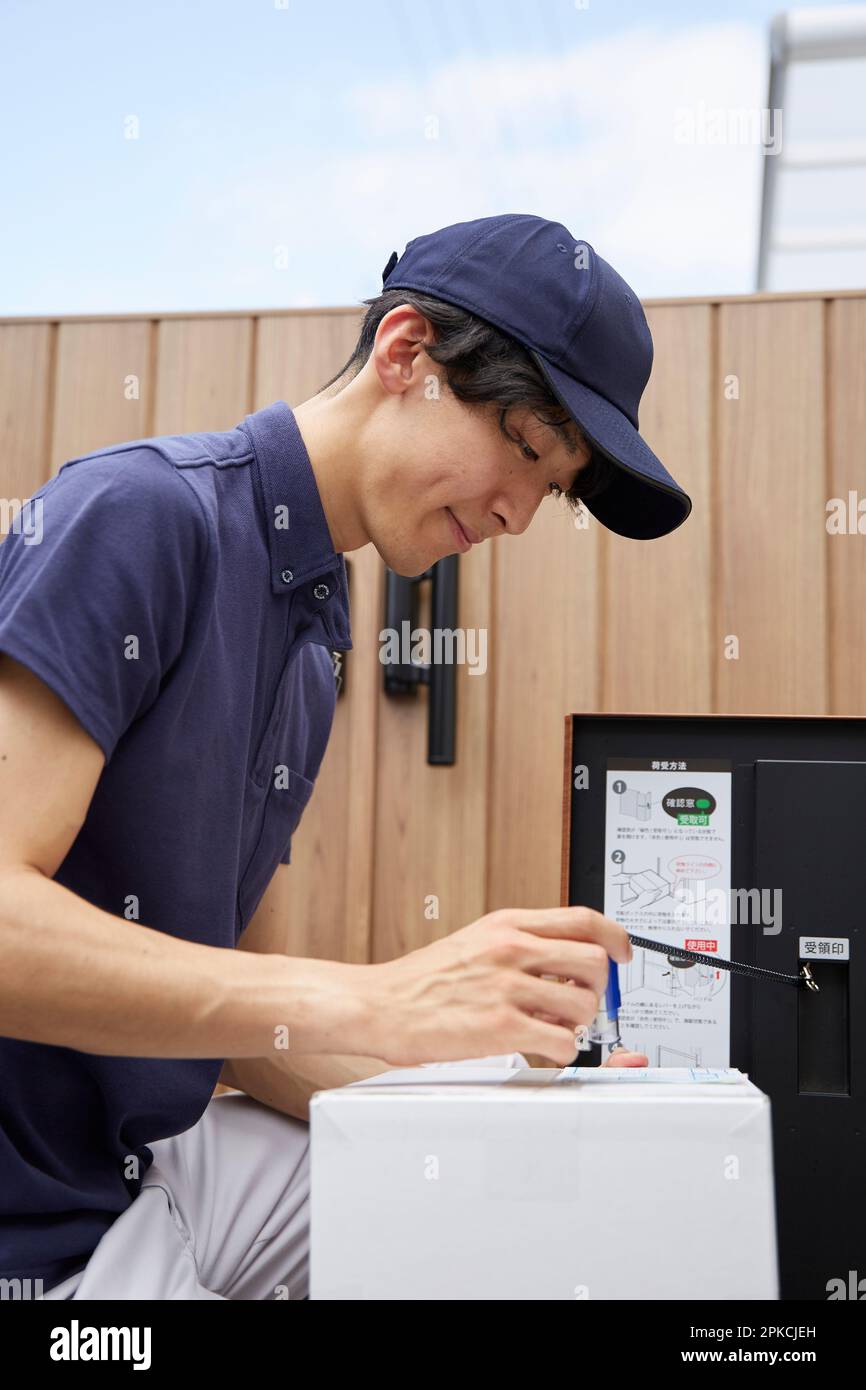 Delivery man putting a package in a delivery box Stock Photo - Alamy