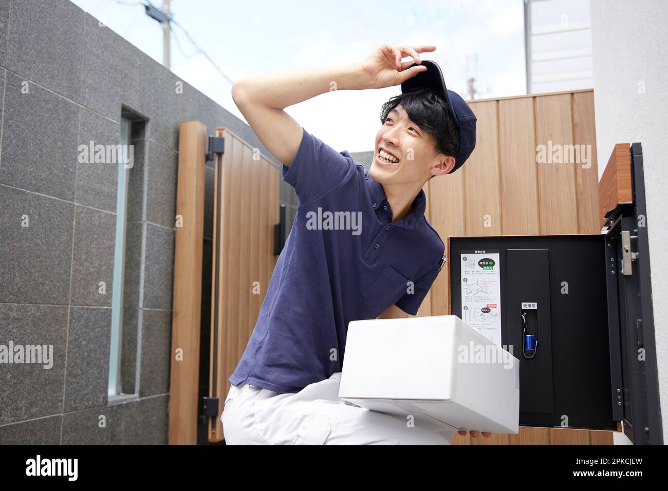 Delivery man putting a package in a delivery box Stock Photo - Alamy