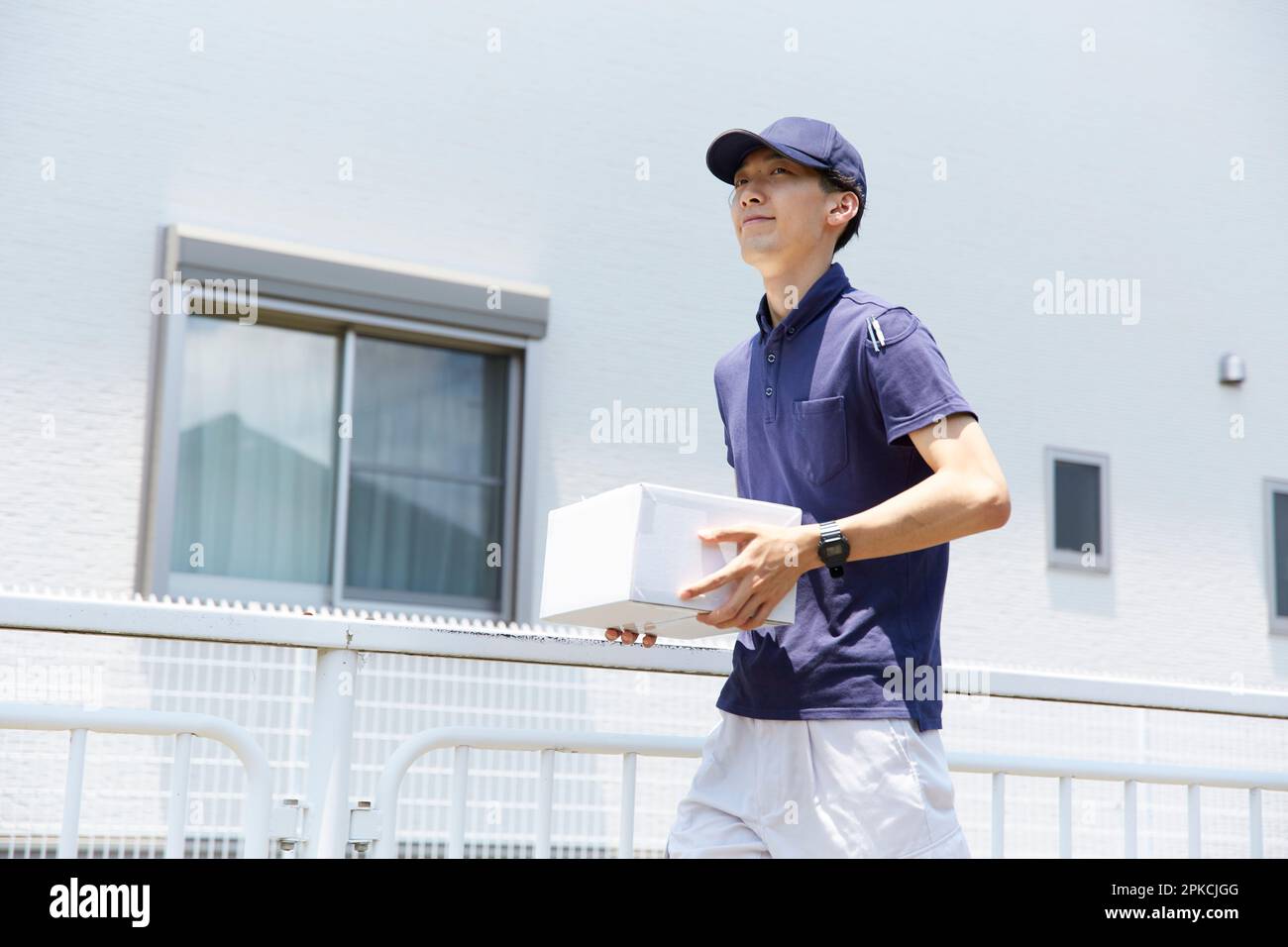 Male delivery man carrying a package Stock Photo - Alamy