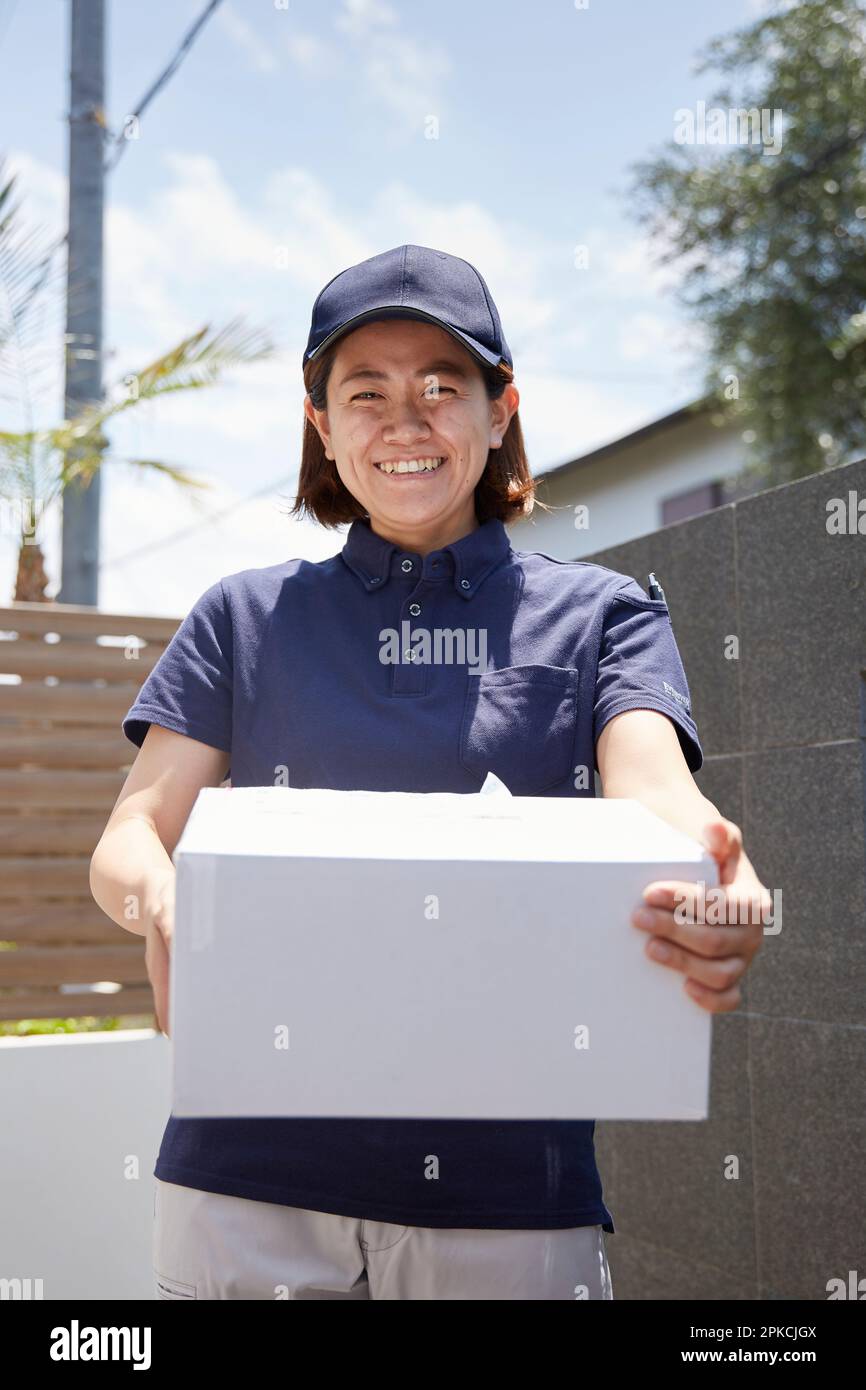 Delivery woman carrying a package Stock Photo - Alamy