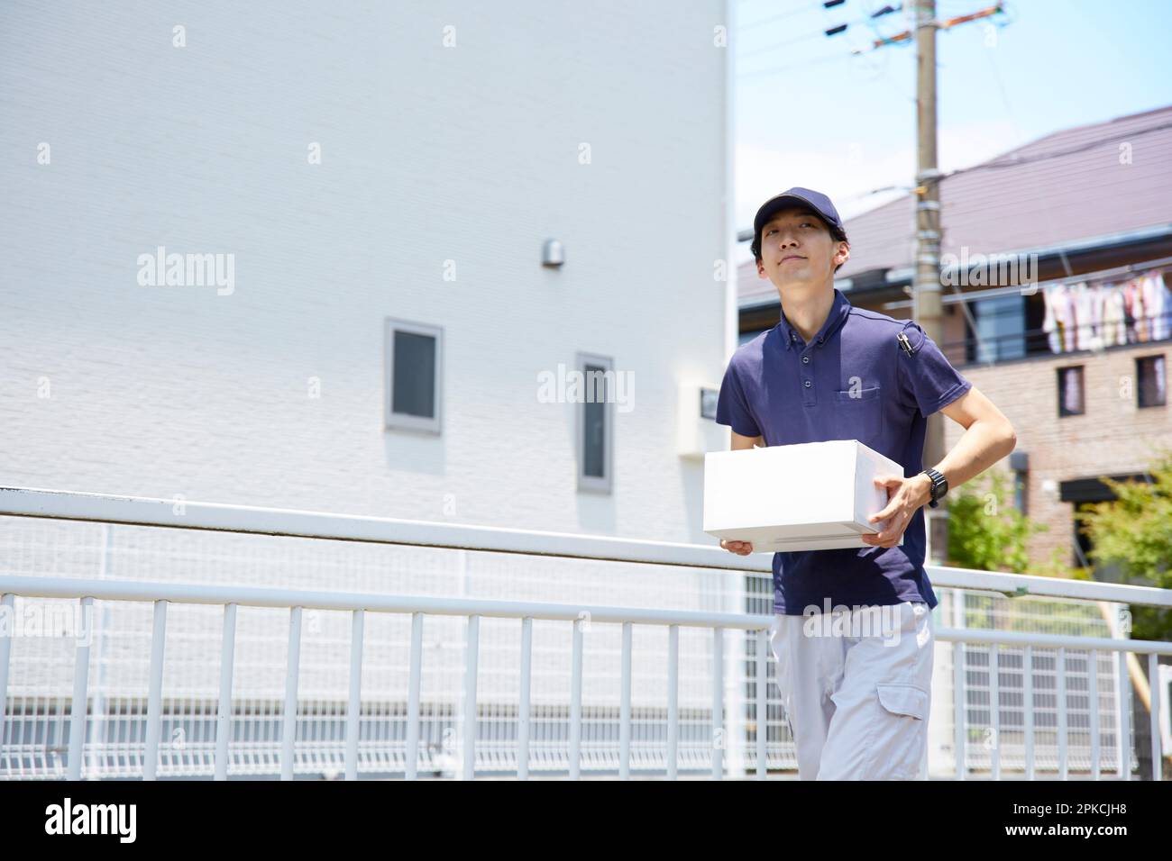 Male delivery man carrying a package Stock Photo - Alamy