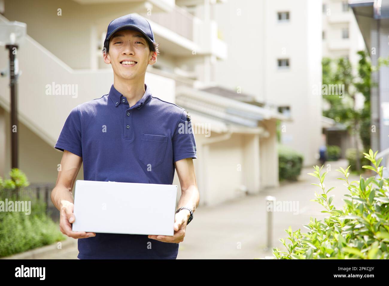 Male delivery man carrying a package Stock Photo - Alamy