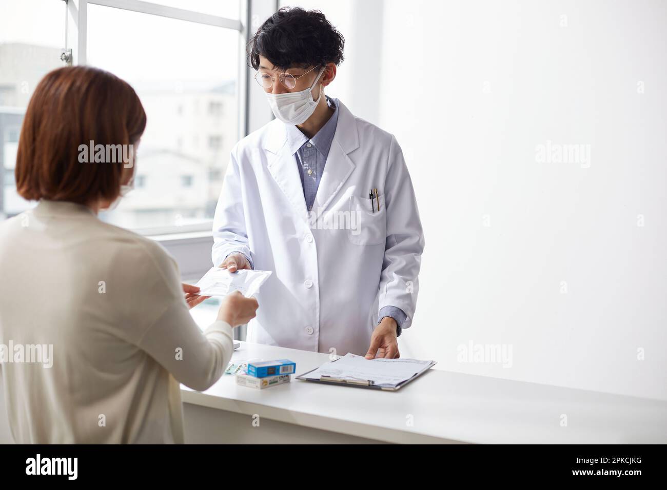 Man in white coat and woman in back handing medicine over counter Stock ...