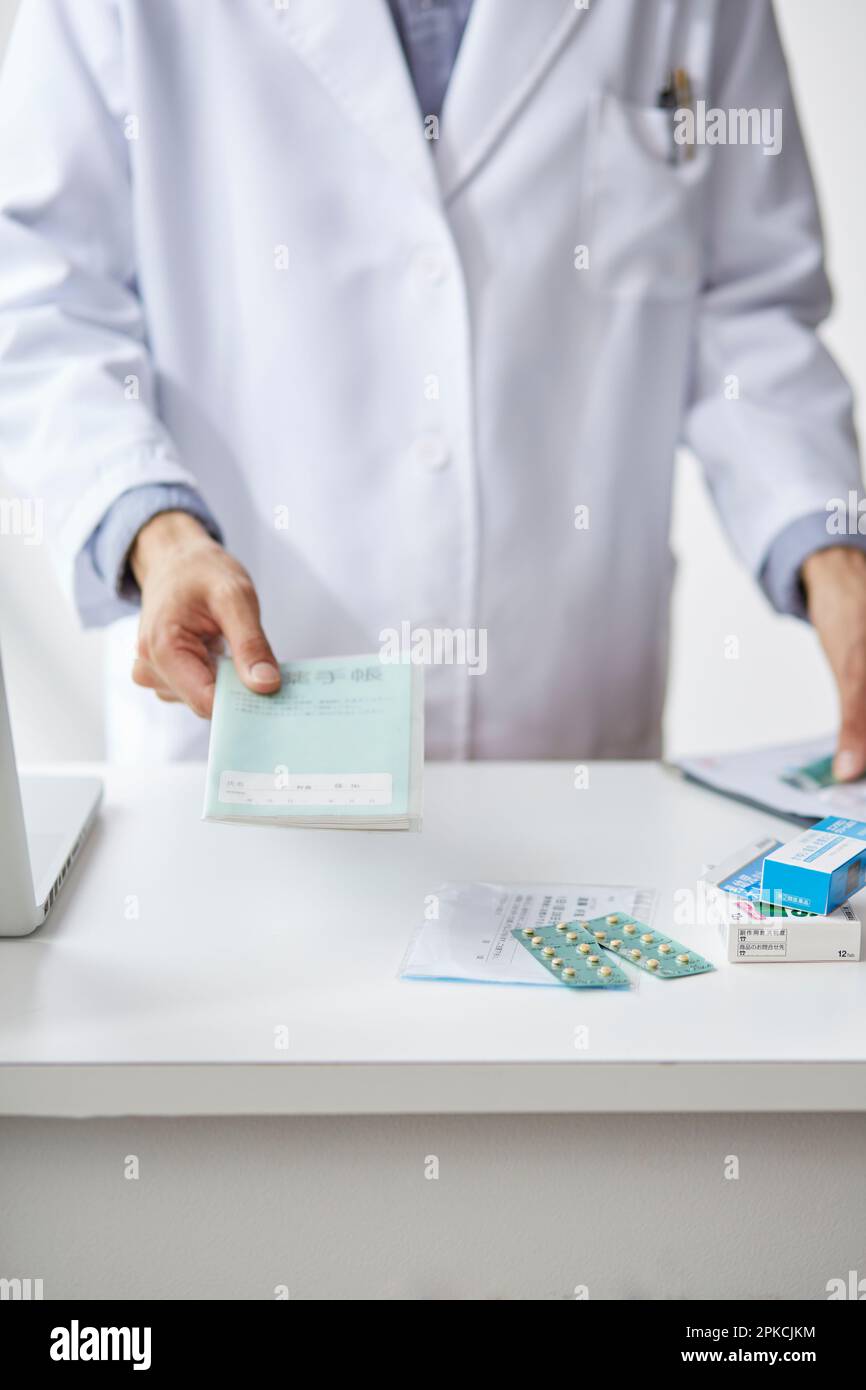 Man in white holding out a medication book at the counter Stock Photo ...