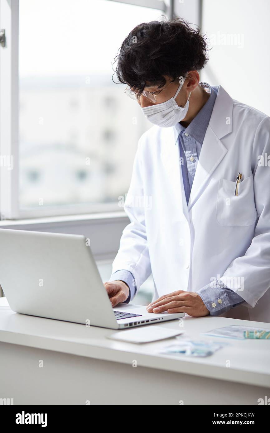 Man in lab coat typing on laptop computer Stock Photo - Alamy