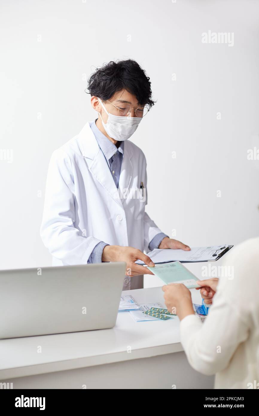 Man in white handing medicine book over counter Stock Photo - Alamy