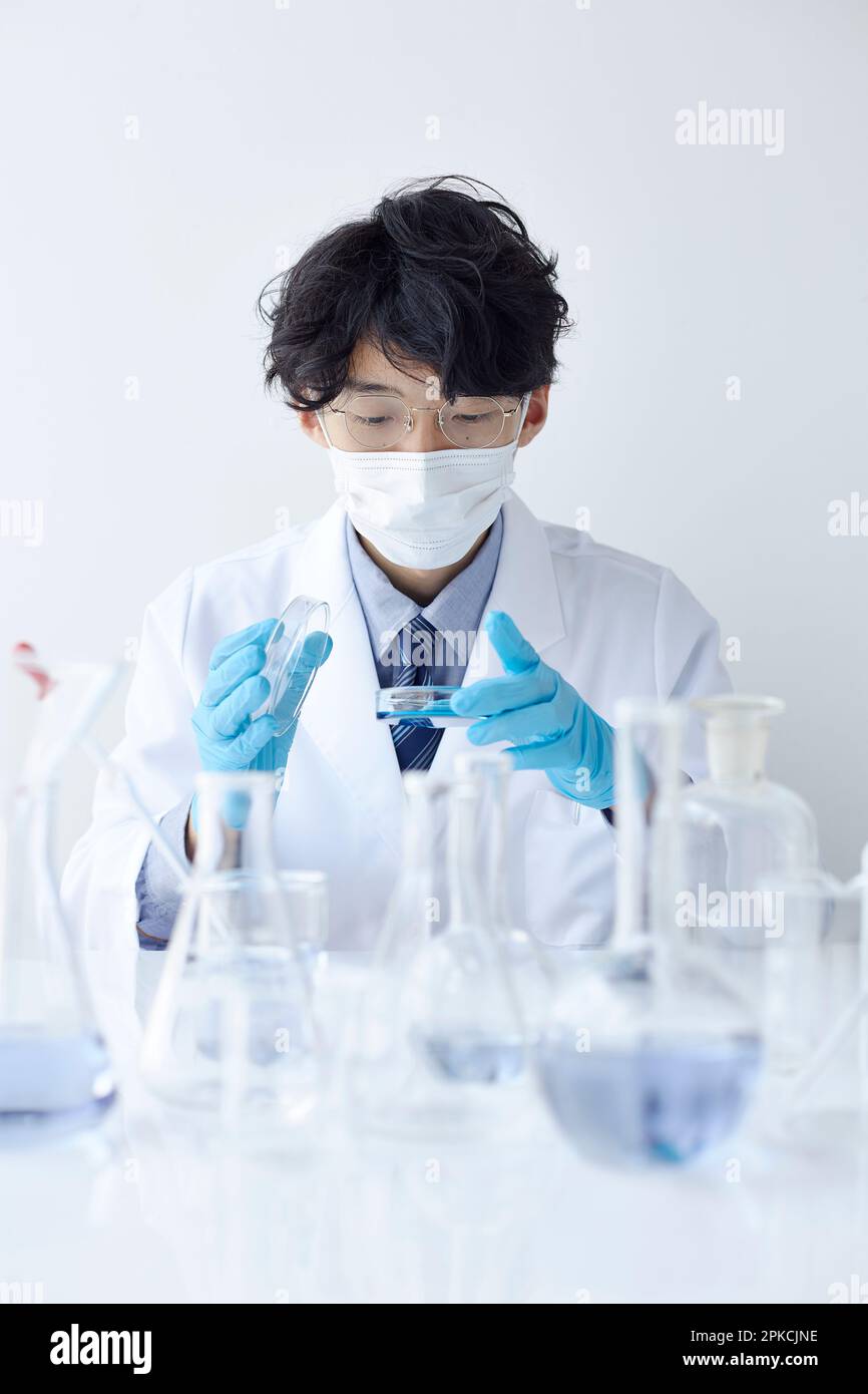 Man wearing a white lab coat experimenting in a white space Stock Photo ...