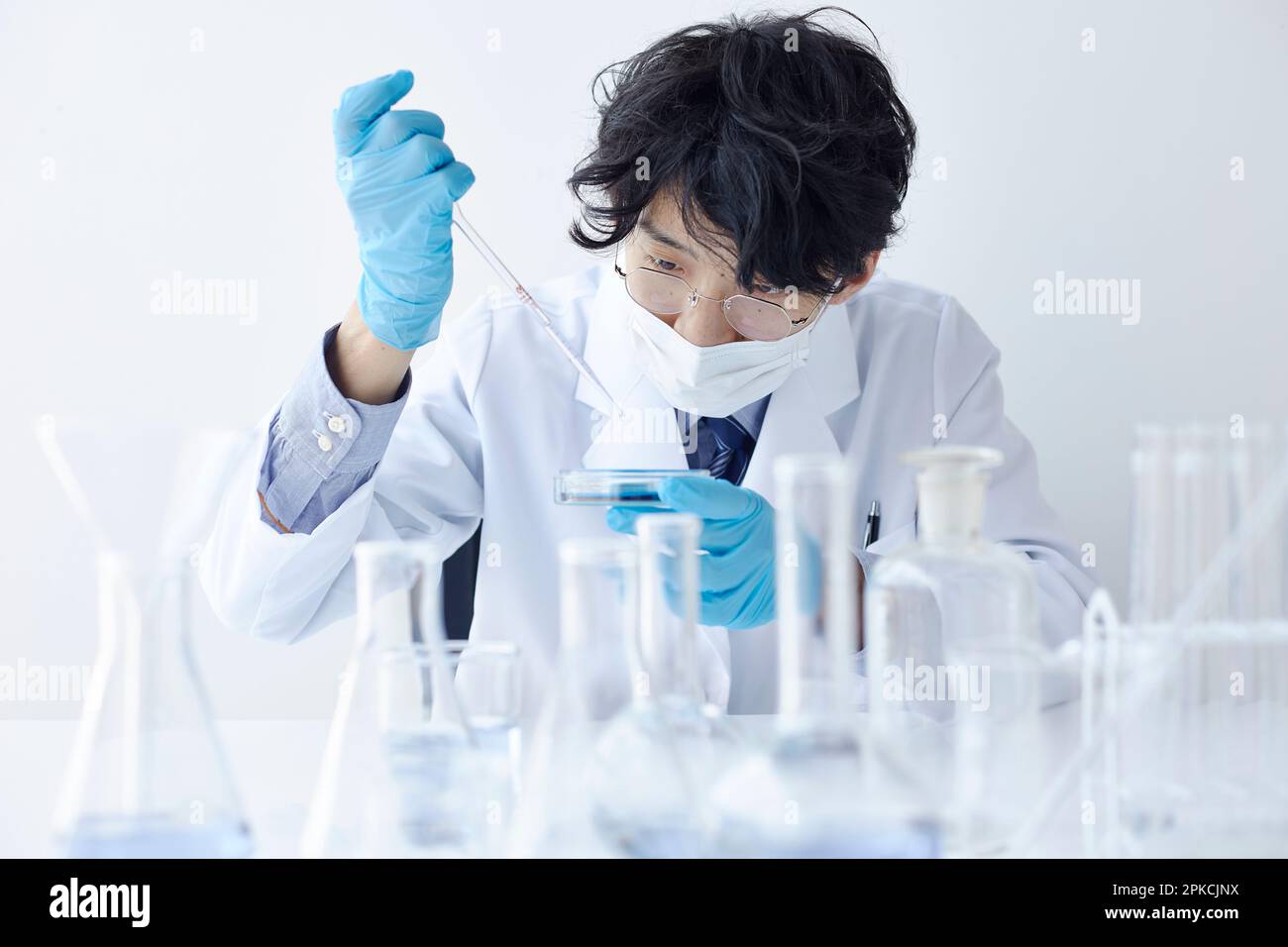 Man in lab coat doing an experiment in a white space Stock Photo - Alamy