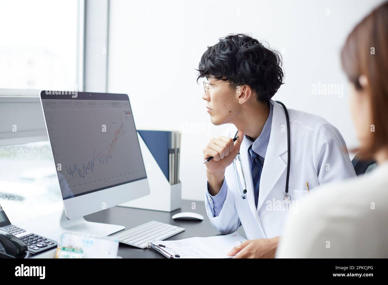 Man in white staring intently at a computer monitor Stock Photo - Alamy