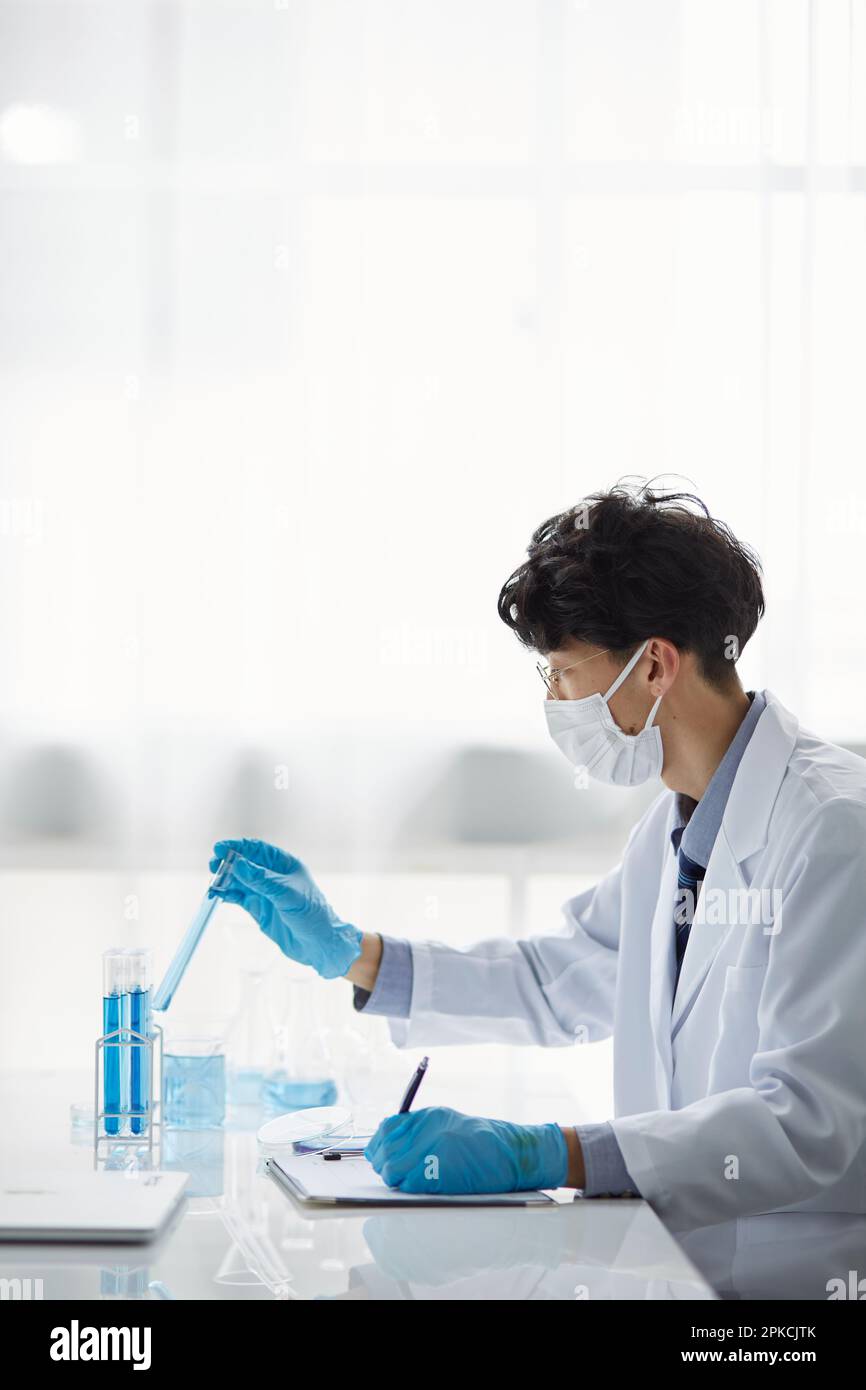 Man wearing white lab coat experimenting in a white space Stock Photo ...