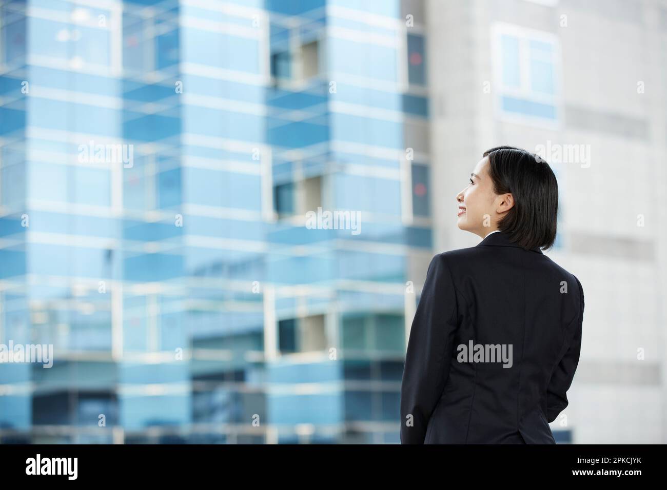 Back view of smiling woman in recruit suit with background of building ...