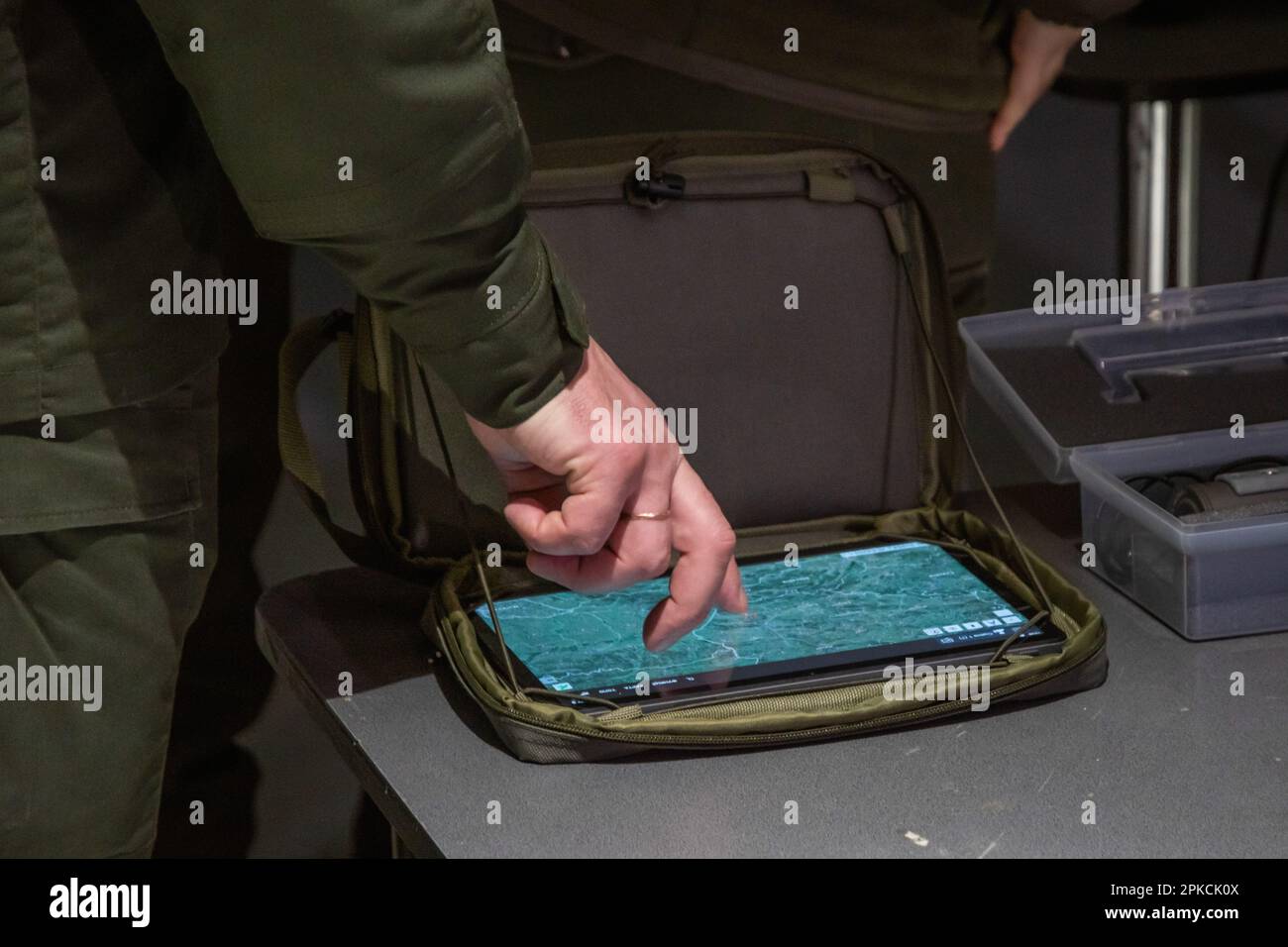A hand of a military man in uniform opens a map of the area on the ...