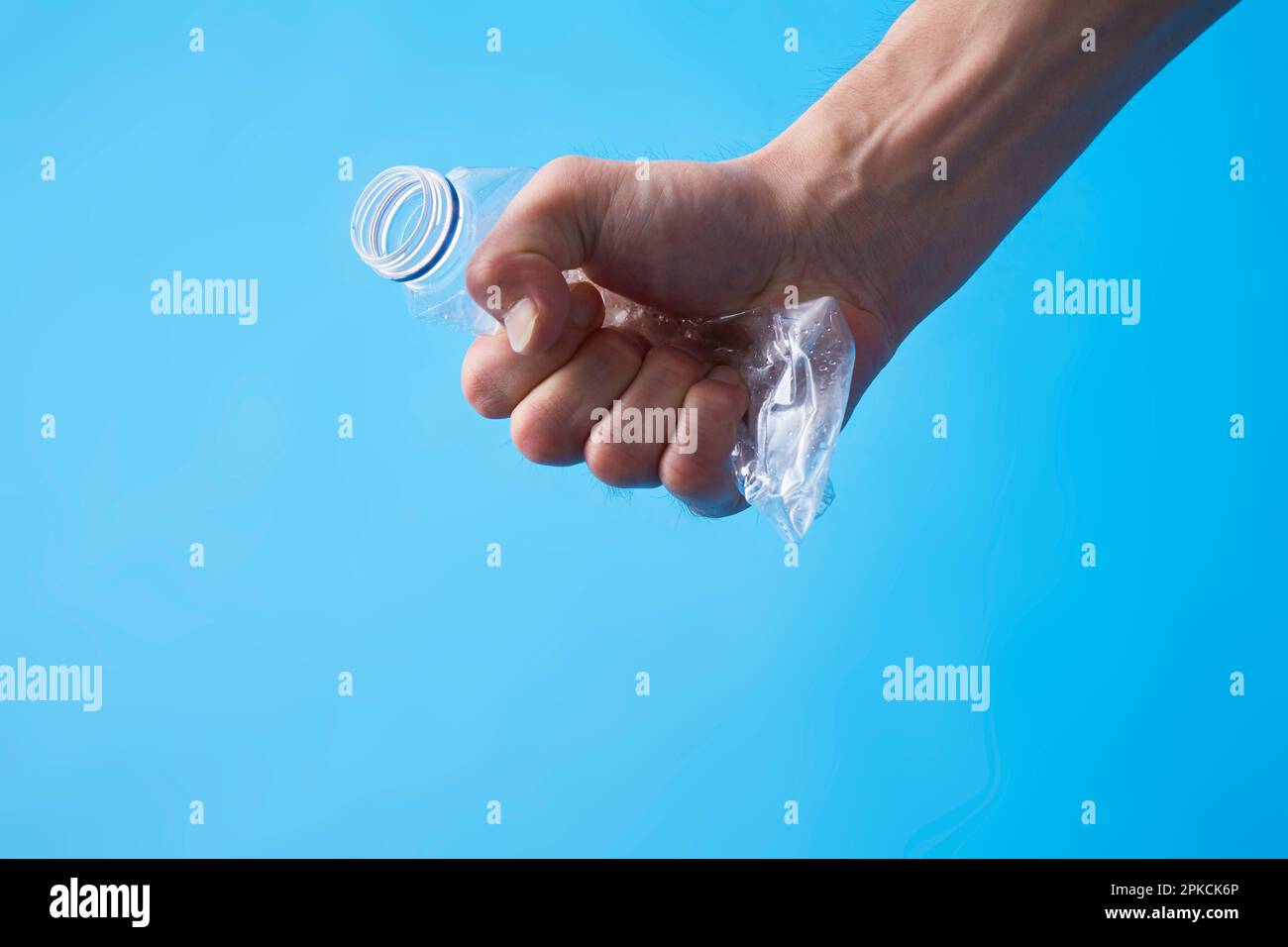 Man's hand clutching an empty plastic bottle Stock Photo - Alamy