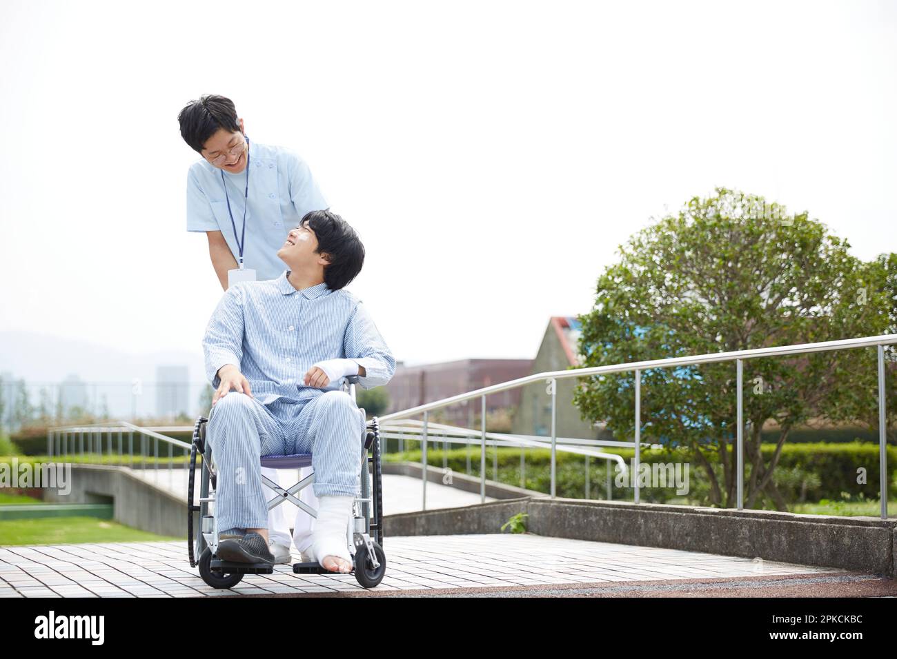 Patient in wheelchair and nurse walking around Stock Photo - Alamy