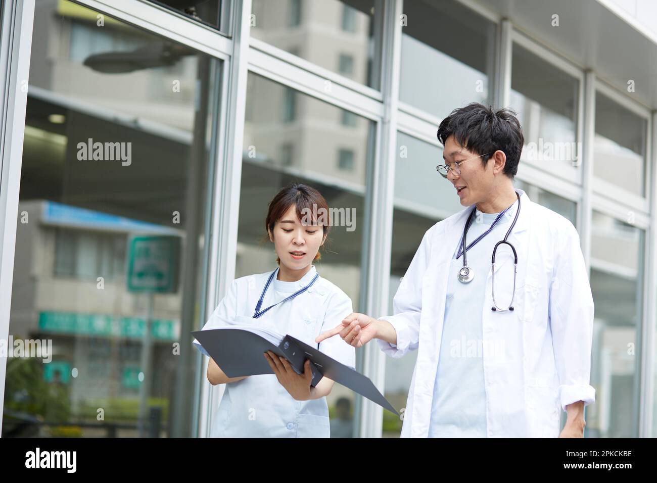 Doctor and nurse looking at file and talking Stock Photo - Alamy