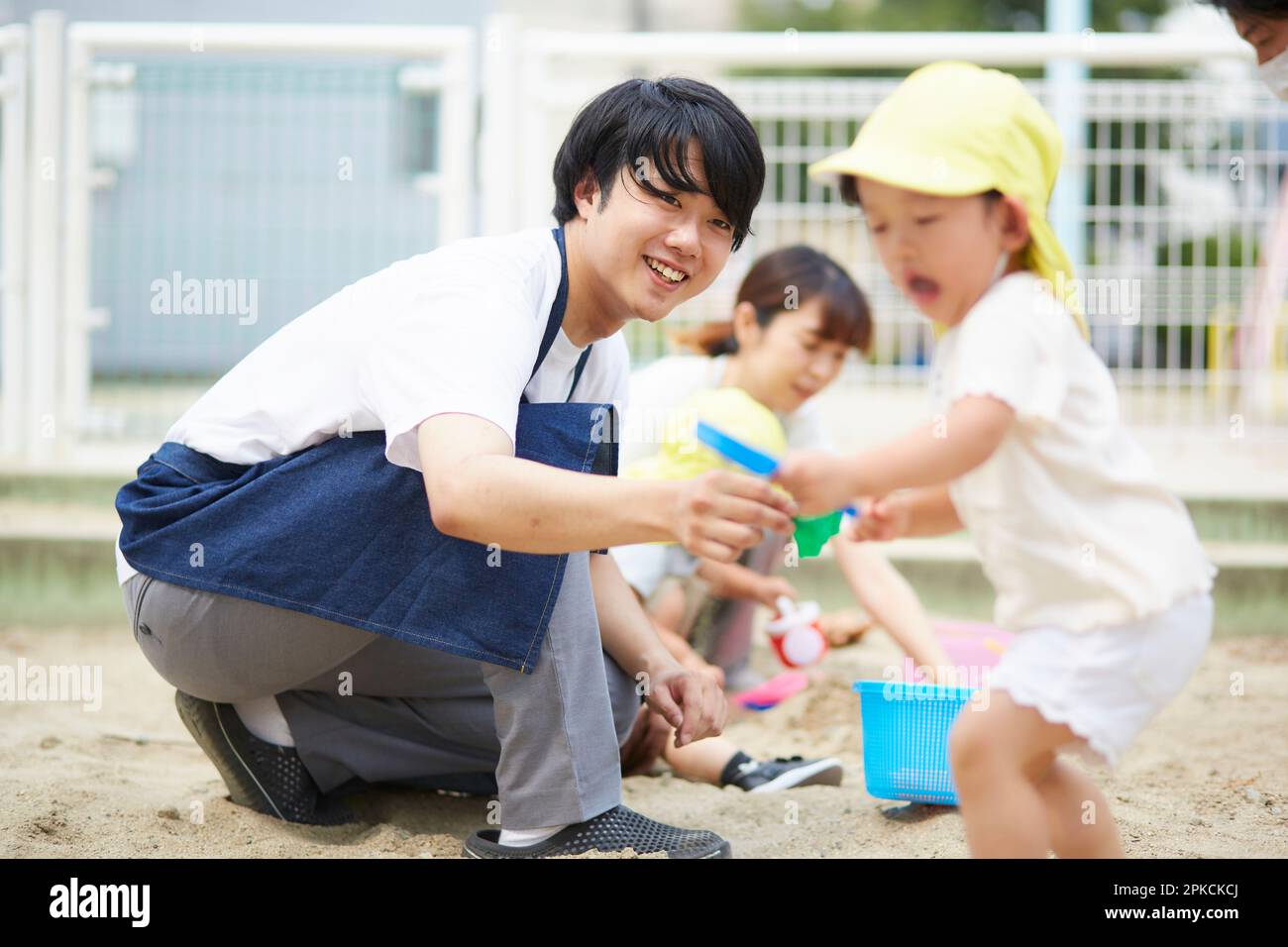 Nursery school teacher and children playing in the sandbox Stock Photo ...