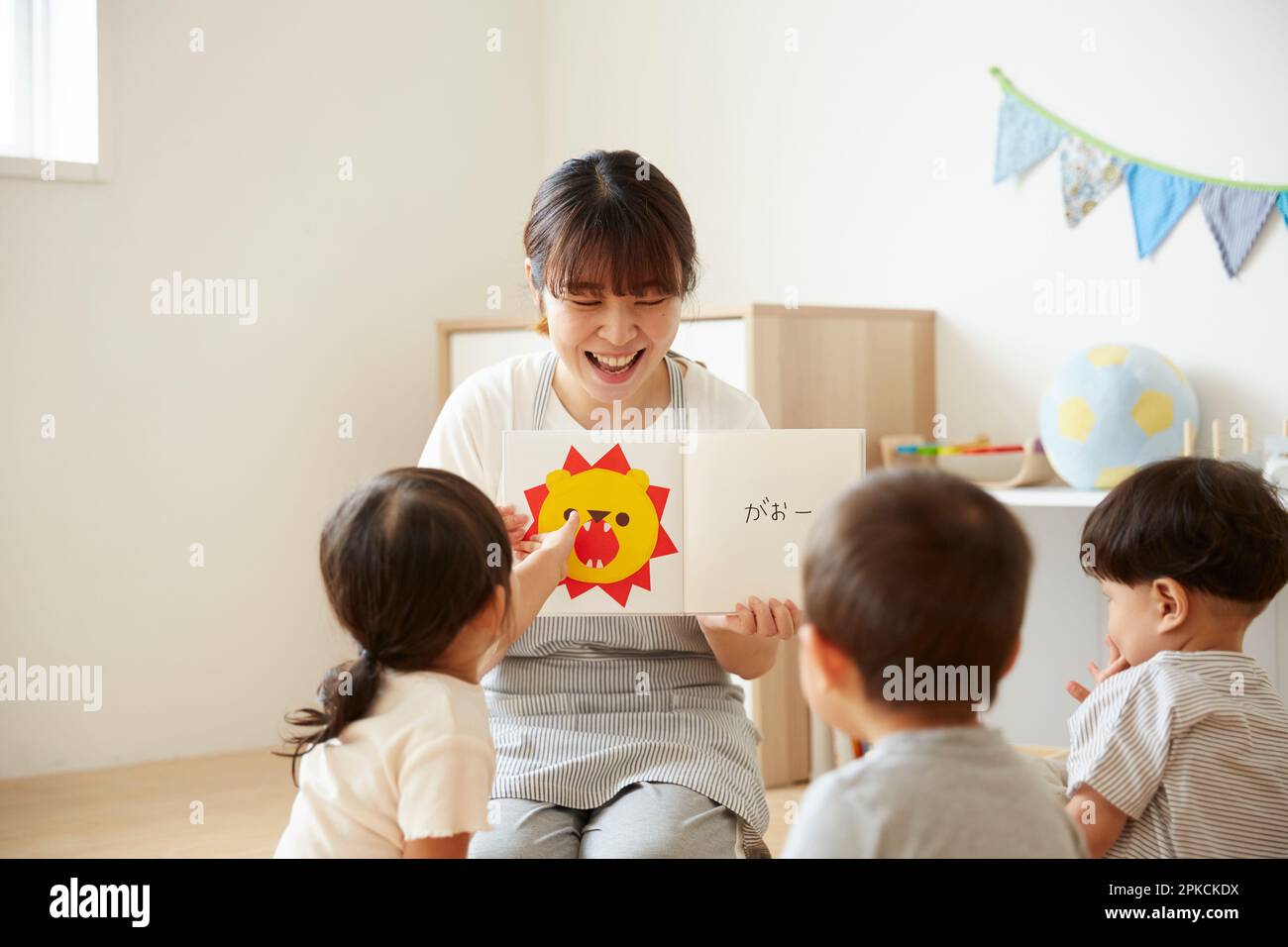 Nursery school teacher reading a story to children Stock Photo - Alamy