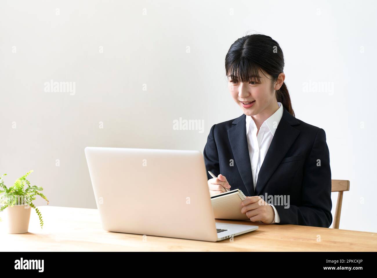 Female job hunter jotting down notes during an online interview on a ...
