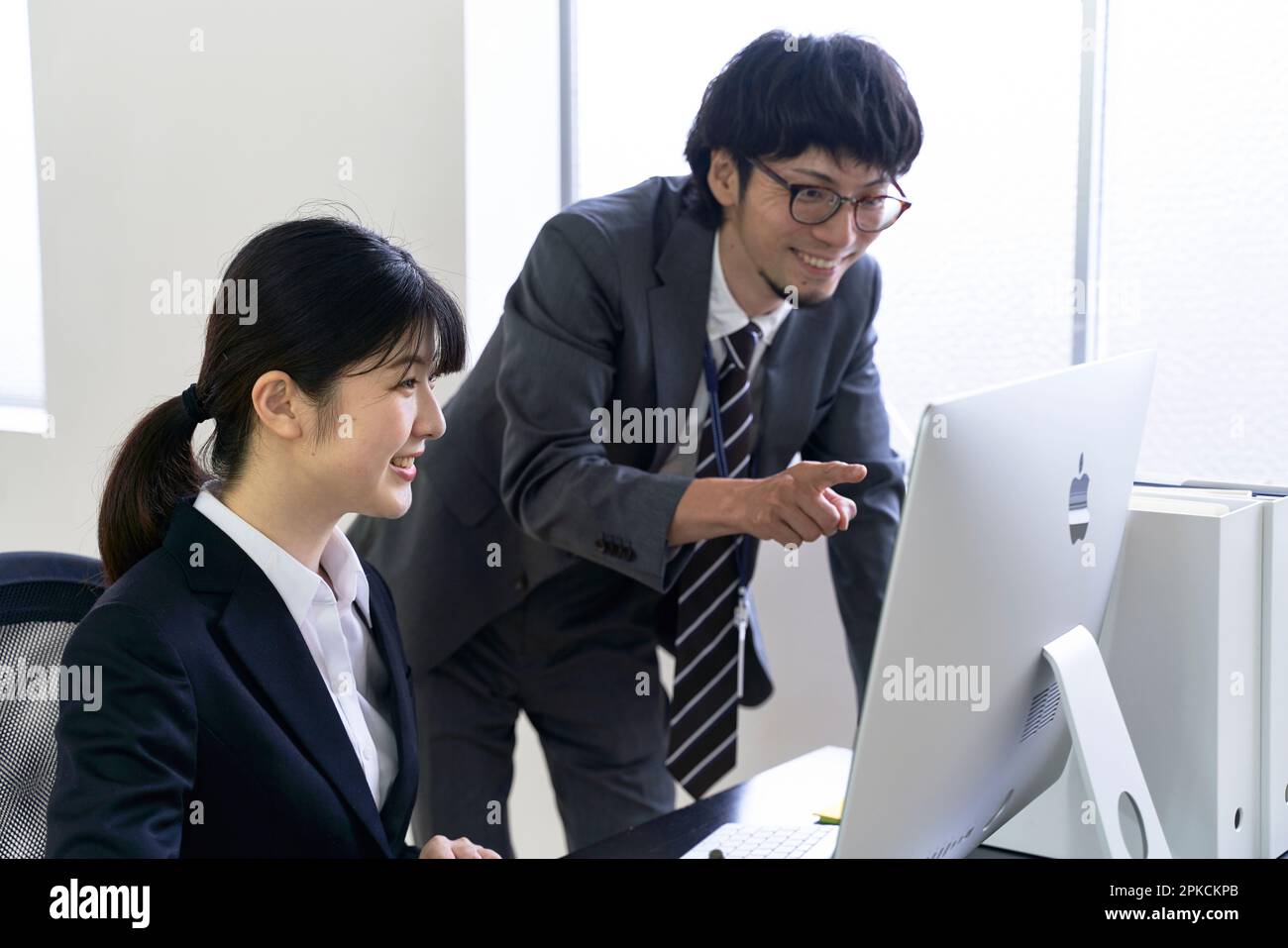 A new female employee operating a computer while being taught her job ...