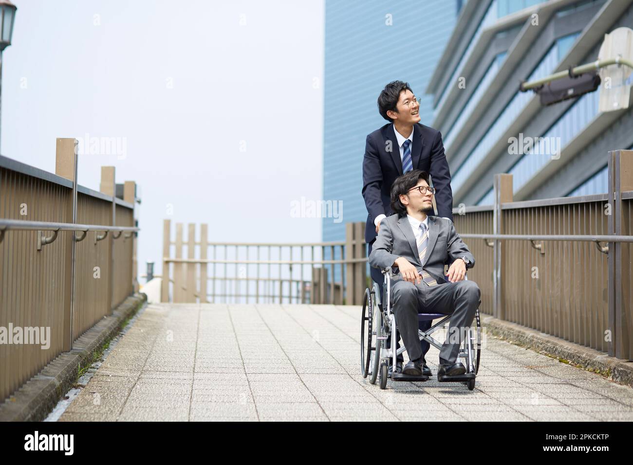 Man in suit pushing man in wheelchair Stock Photo - Alamy